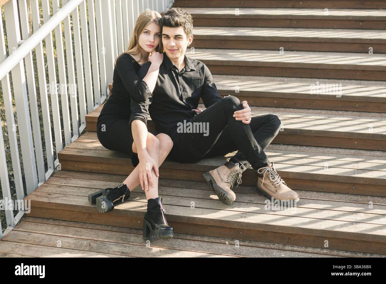 Beautiful young multiracial couple, student couple in love, sit wooden ...