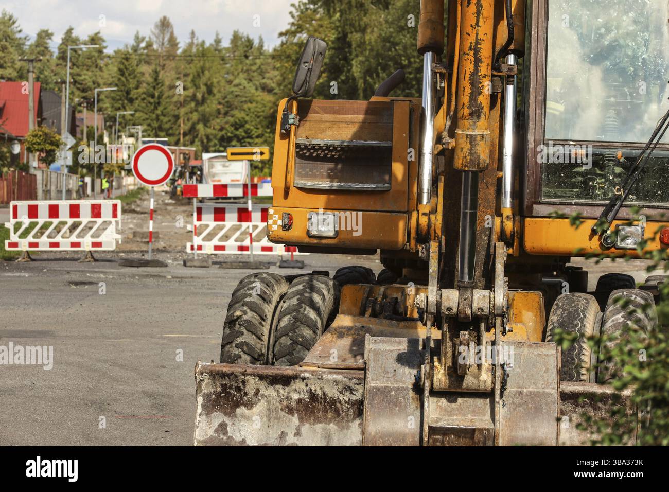 Detail on old yellow digger machine back, driver cabin visible, road ...