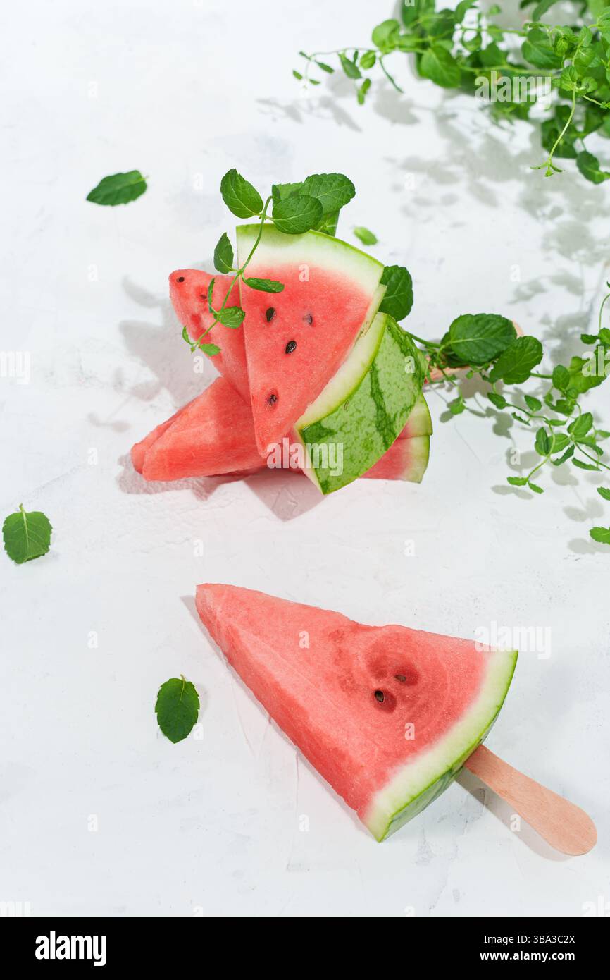 Multiple watermelon wedges layered with fresh mint on white backdrop ...