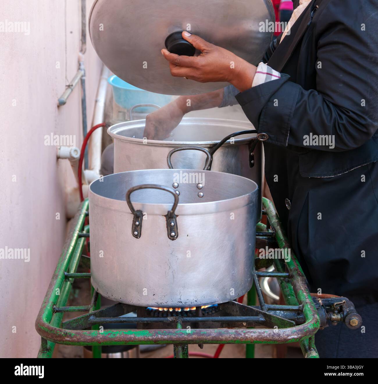 volunteer african woman cooking on gas stove , outdoors kitchen, huge ...