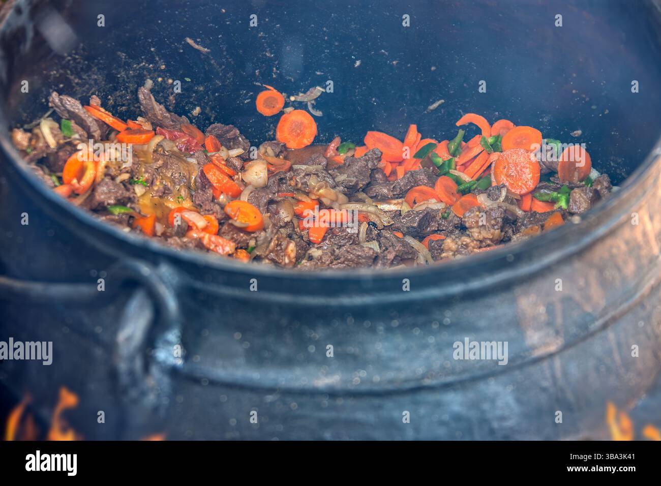 cooking traditional food stew in a three legged pot cauldron outdoors ...