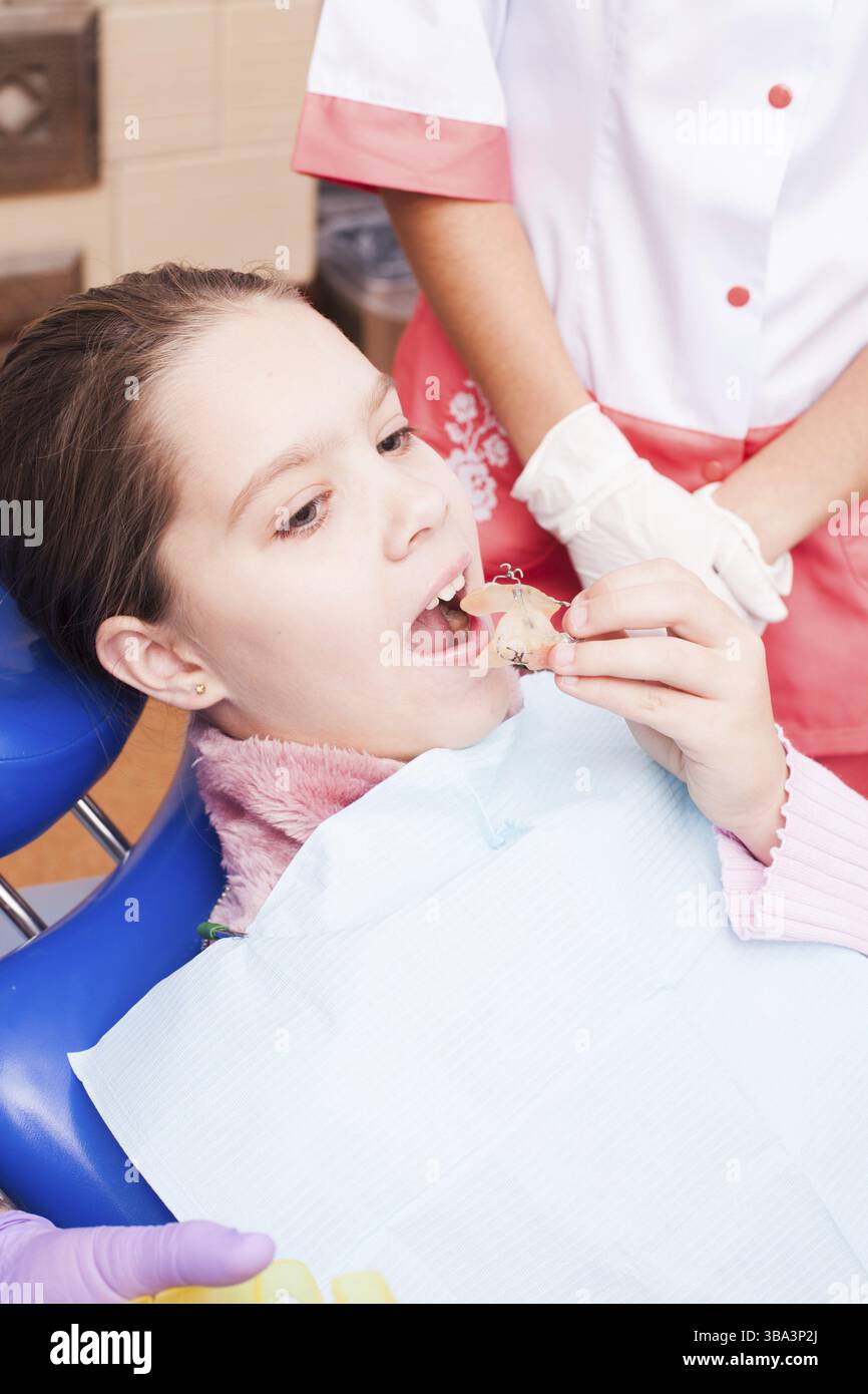 A girl tries to establish a retainer for Teeth Dental Braces, sitting ...