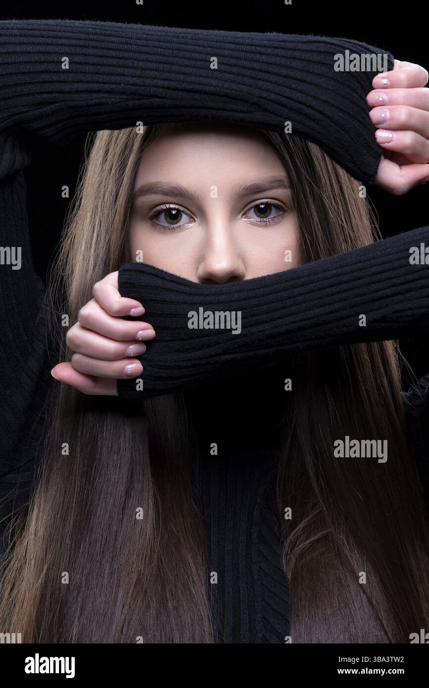 A beautiful brunette girl covered her face with her hands, leaving only ...