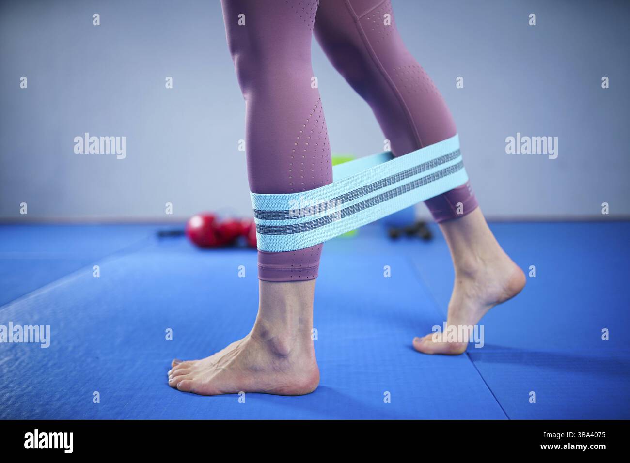 Athletic woman in sportswear barefoot using thick elastic fabric ...