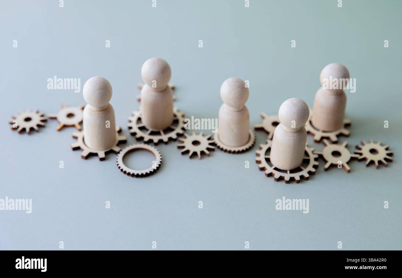 A conceptual image with wooden figures standing on interconnected gears ...