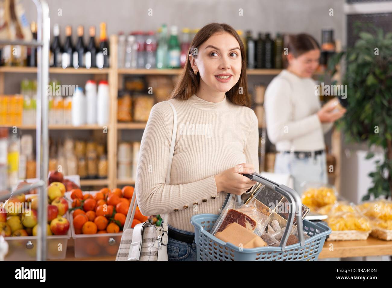 Visiting store woman is looking at something on shelf of showcase ...