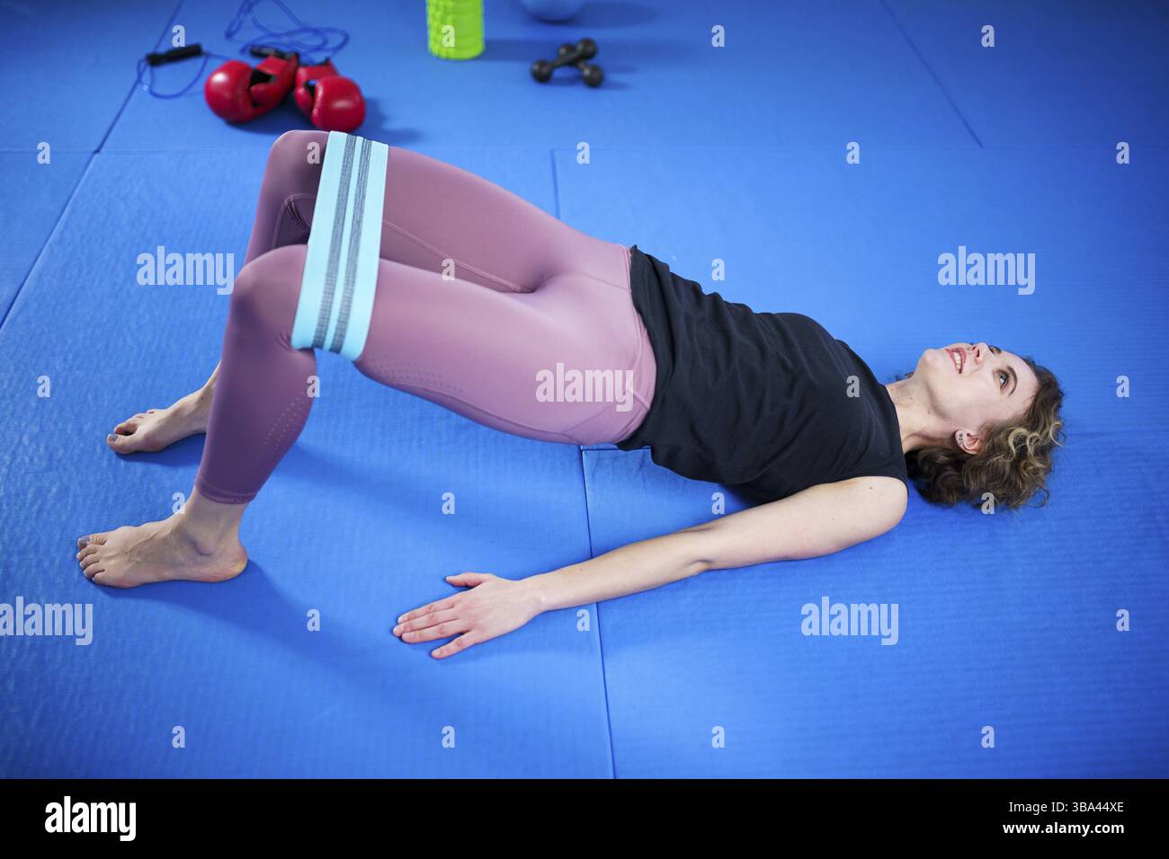 Athletic woman in sportswear barefoot using thick elastic fabric ...