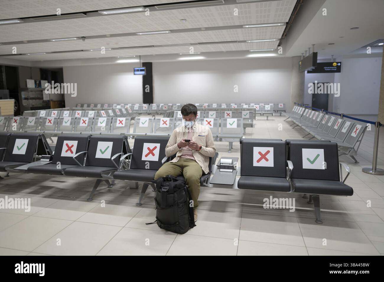 Waiting for flight at empty airport in Cyprus. Man sitting on chair ...
