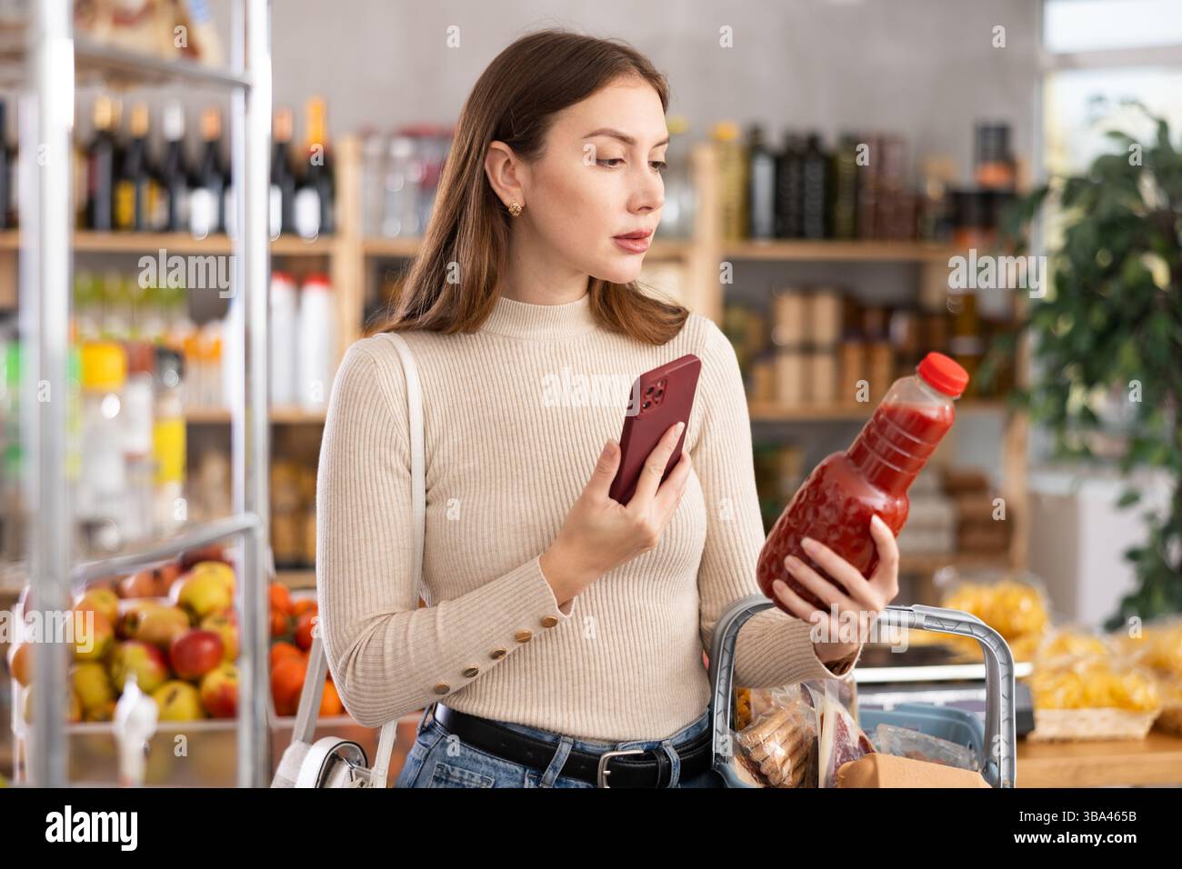 Girl customer holds bottle of tomato juice in hand, scans QR code on ...