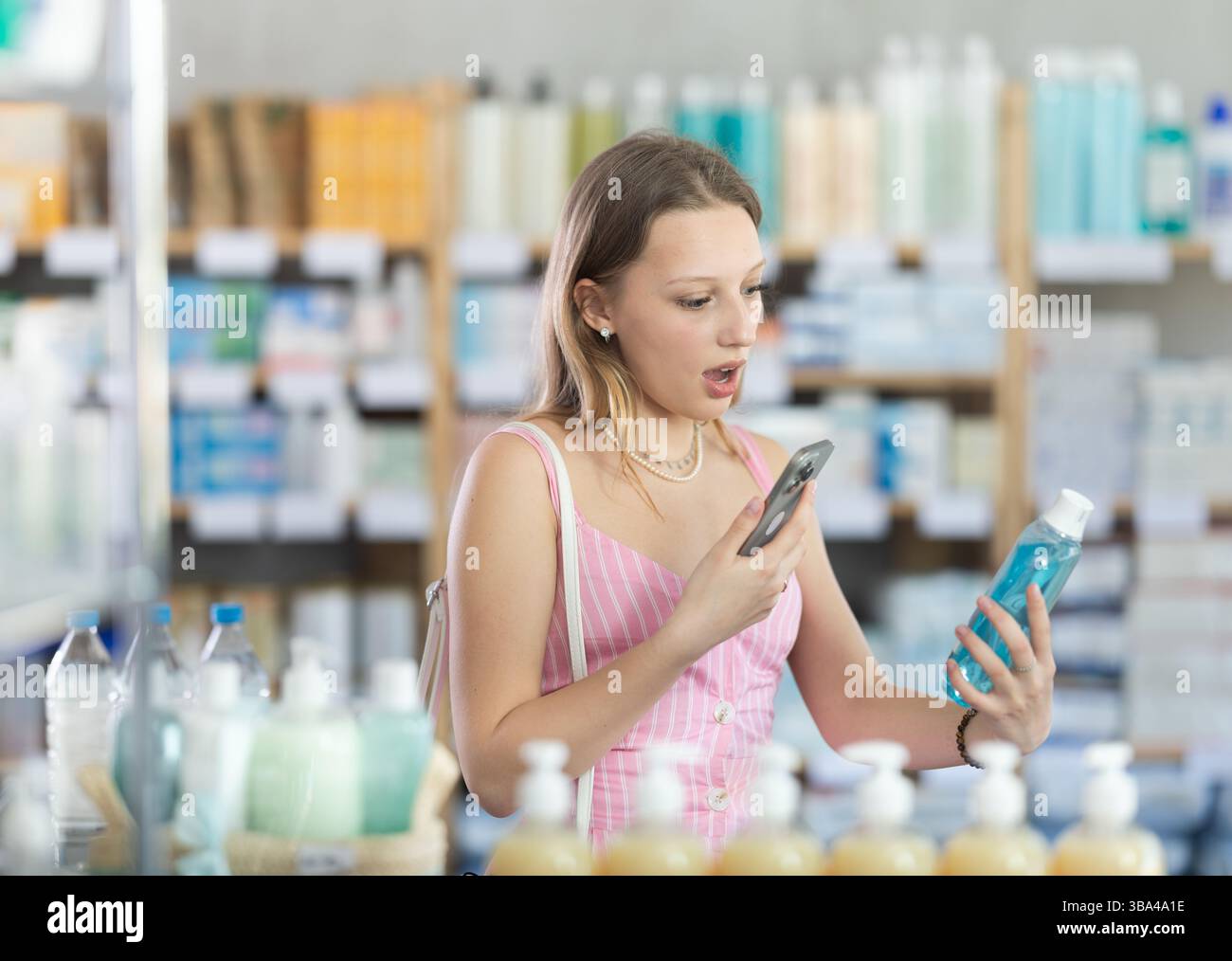 Blonde woman scanning on mobile bottle with rinse aid Stock Photo - Alamy