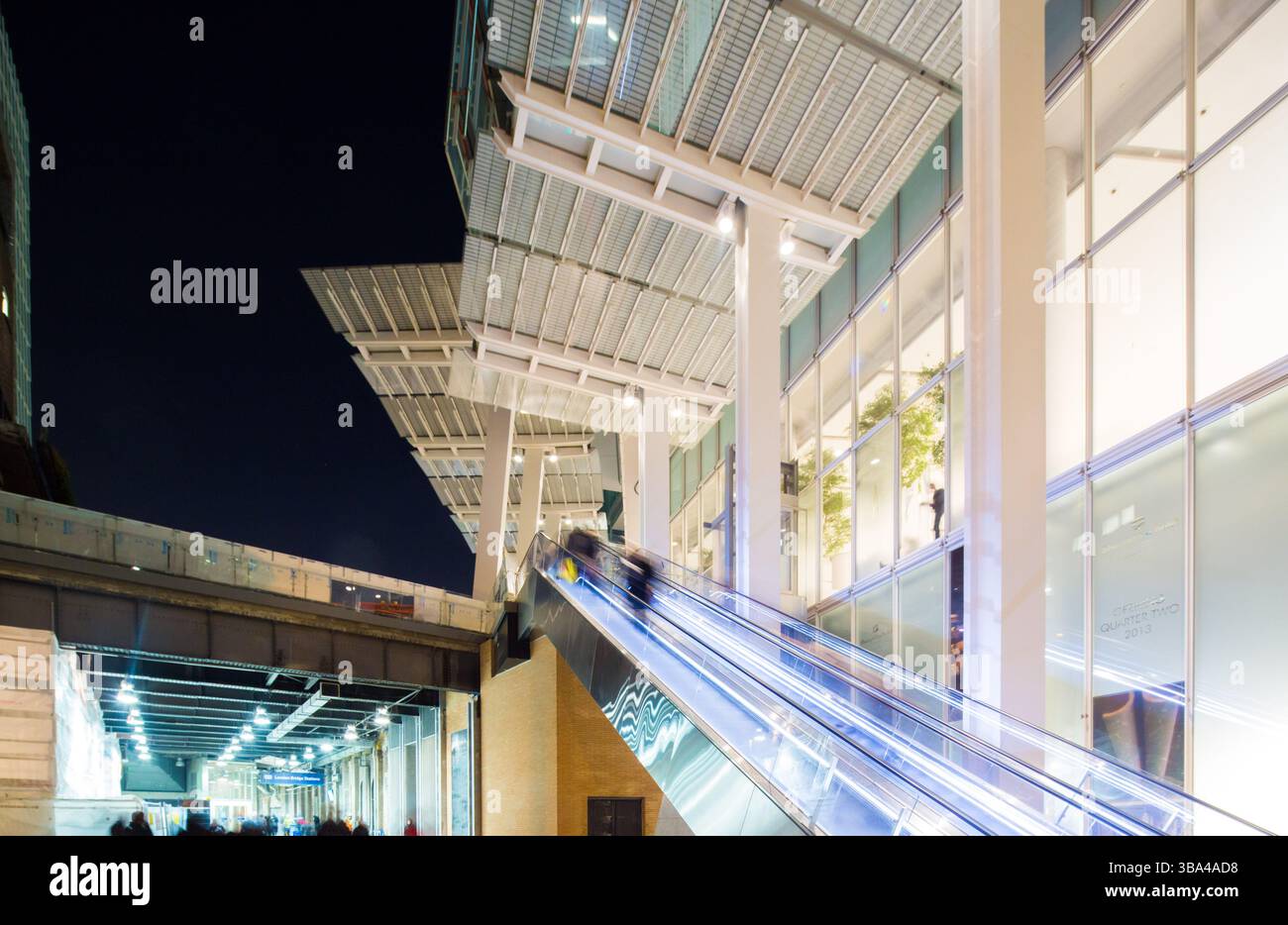 Night scene at London Bridge Station. Commuters use the escalator to ...