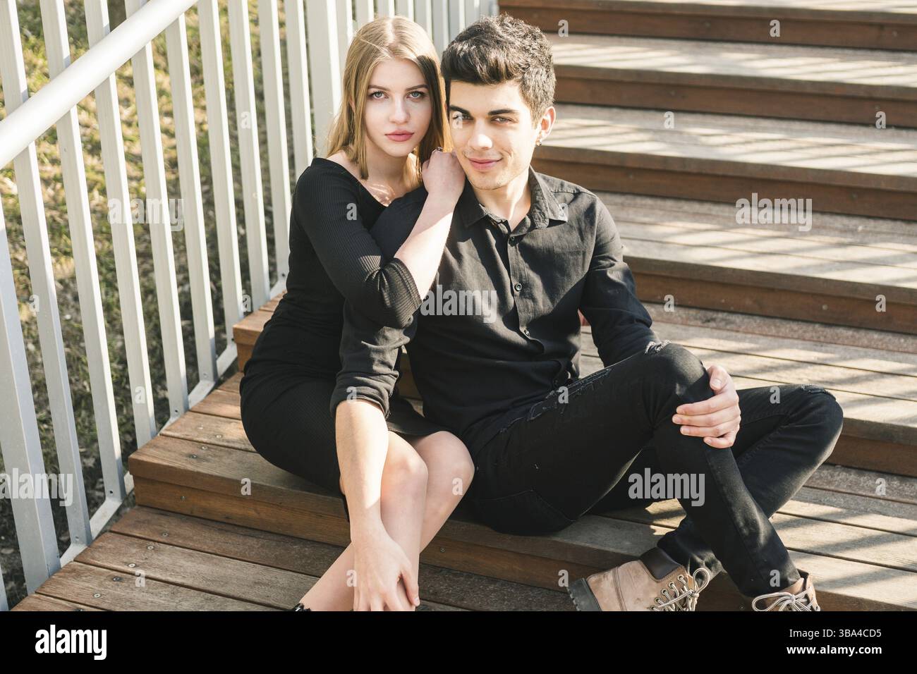 Beautiful young multiracial couple, student couple in love, sit wooden ...