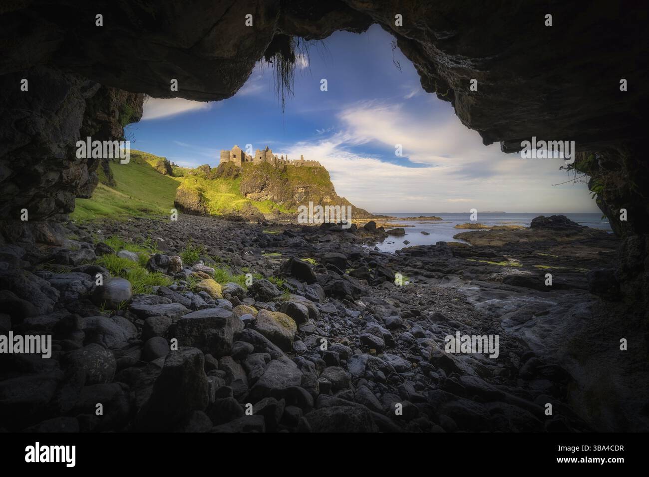 Dunluce Castle seen from a small cave on a shoreline, nested on the ...
