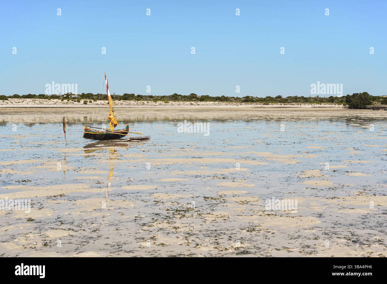 Fisherman piroga small fishing boat with sail waiting at the low tide ...