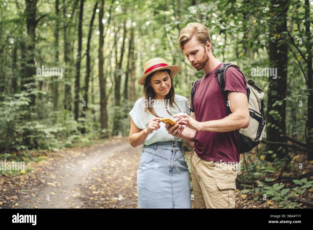 Hikers using mobile gps for directions. Happy couple checking smartphone in the woods during ...
