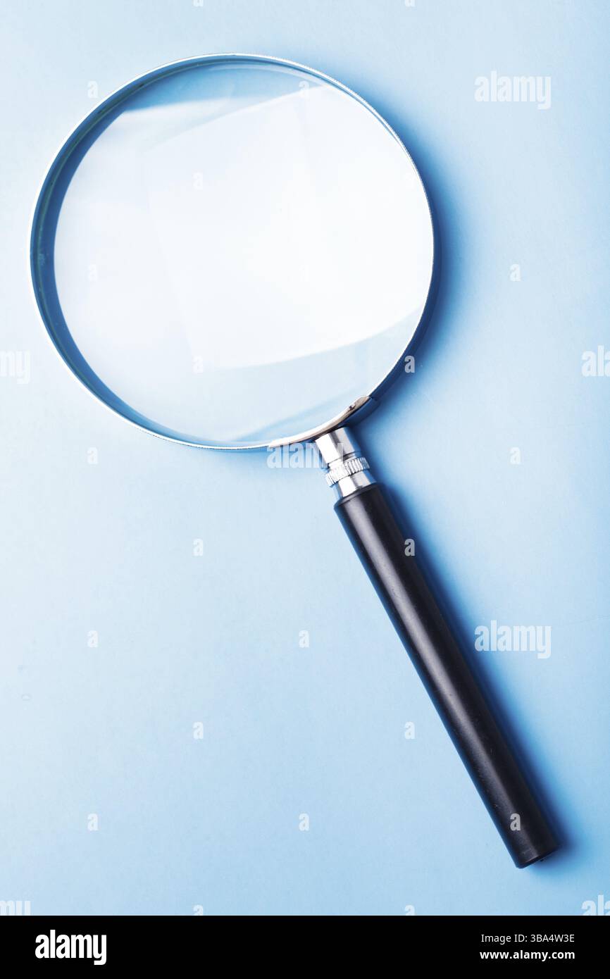 Glass magnifier closeup on a blue background Stock Photo - Alamy