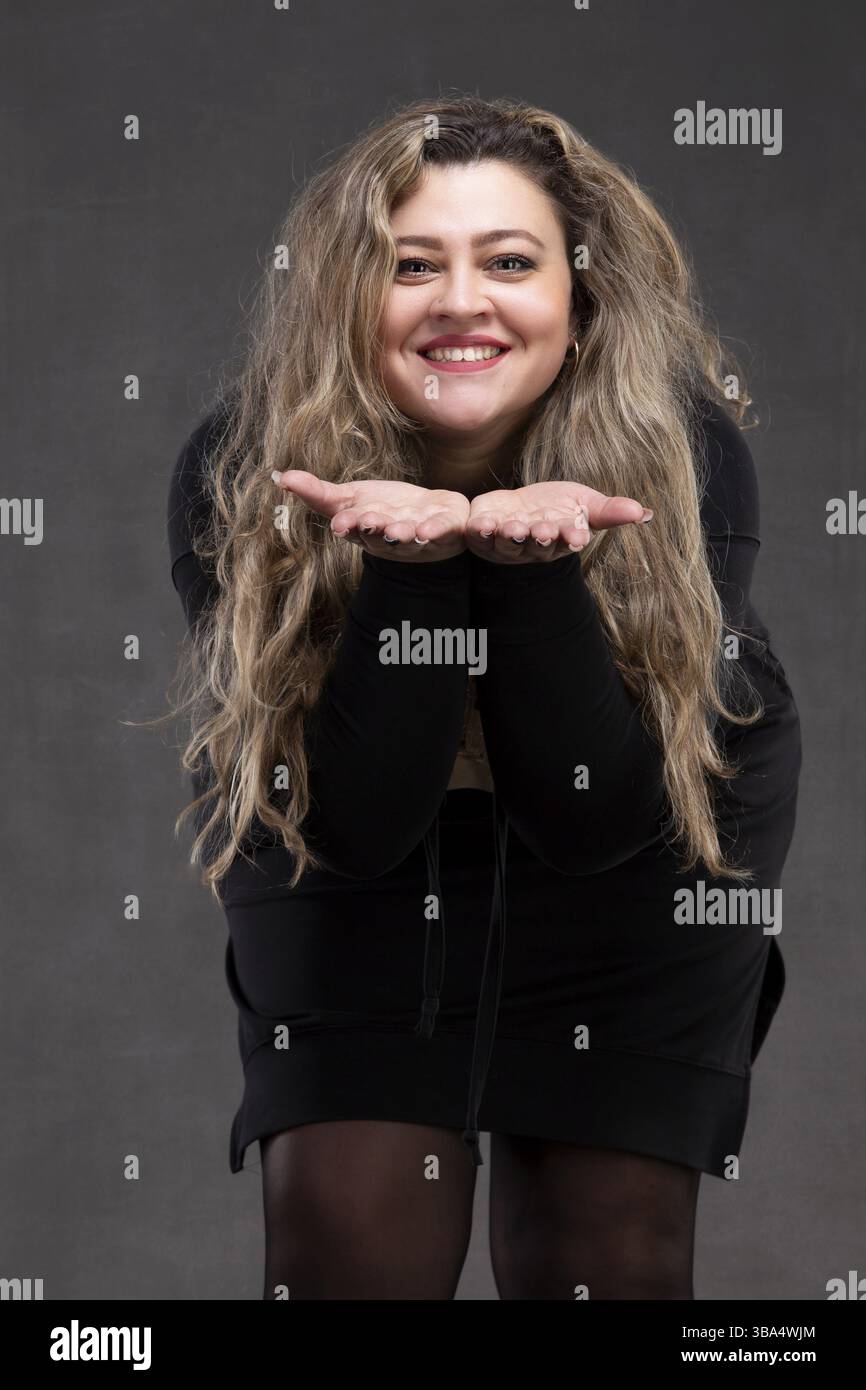 Beautiful fat woman with long curly hair and black dress blowing on her ...