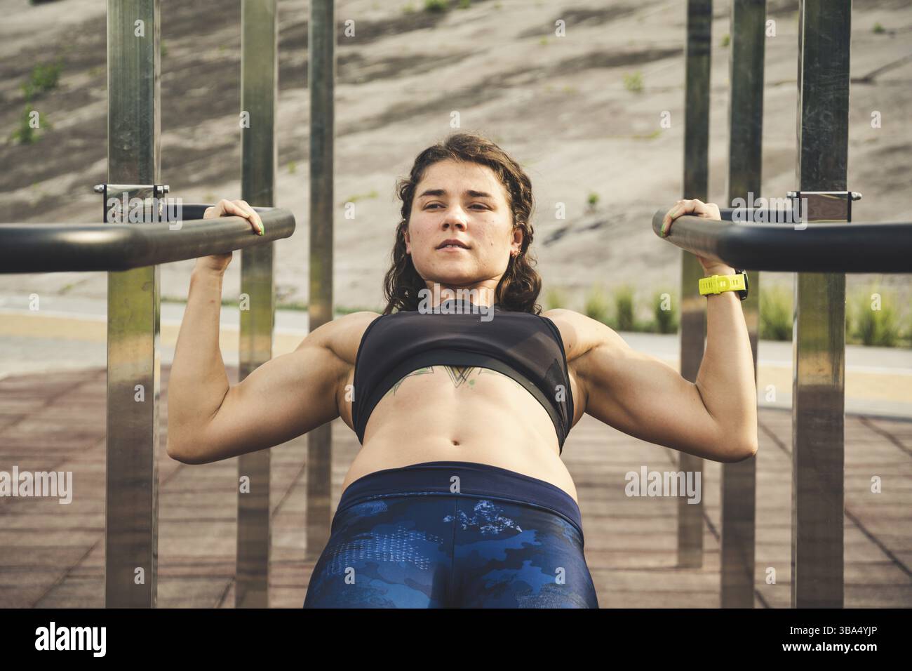Girl trains outdoors in street gym. Training of biceps and triceps ...