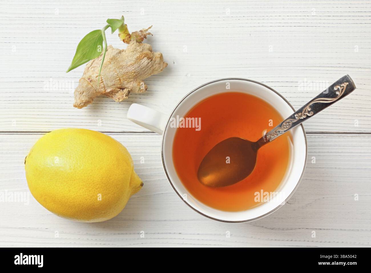 White porcelain cup, silver spoon, hot amber tea in, lemon and dry ...