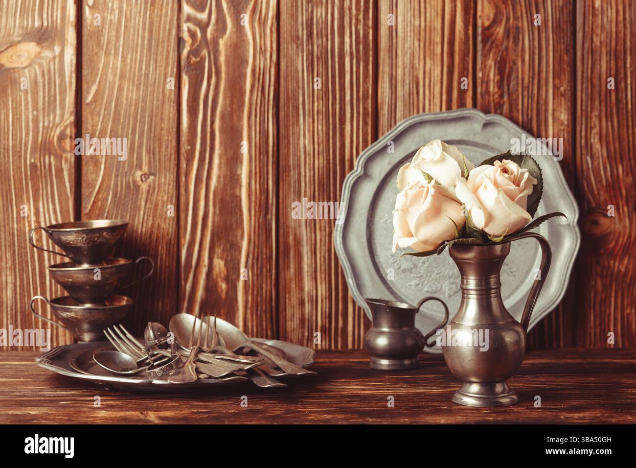 Still life with antique cutlery, plate and flowers in tin jug Stock ...