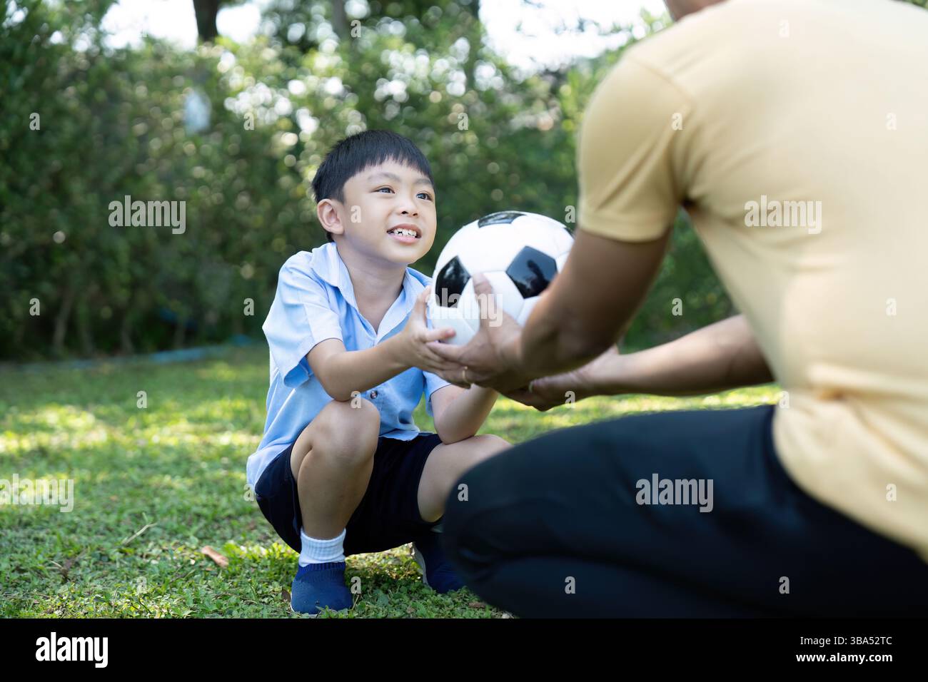 A happy boy receiving a soccer ball from his dad, showcasing wellness ...