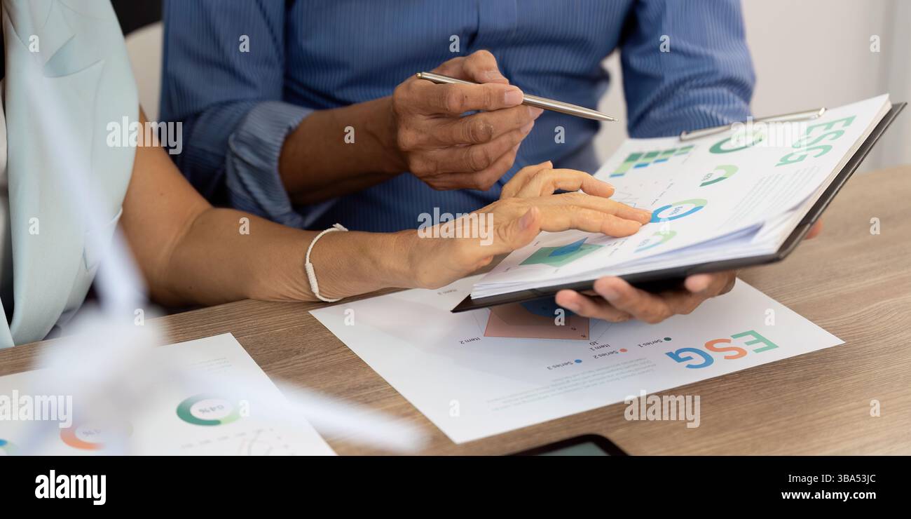 Colleagues collaborating on ESG project data analysis, utilizing charts ...