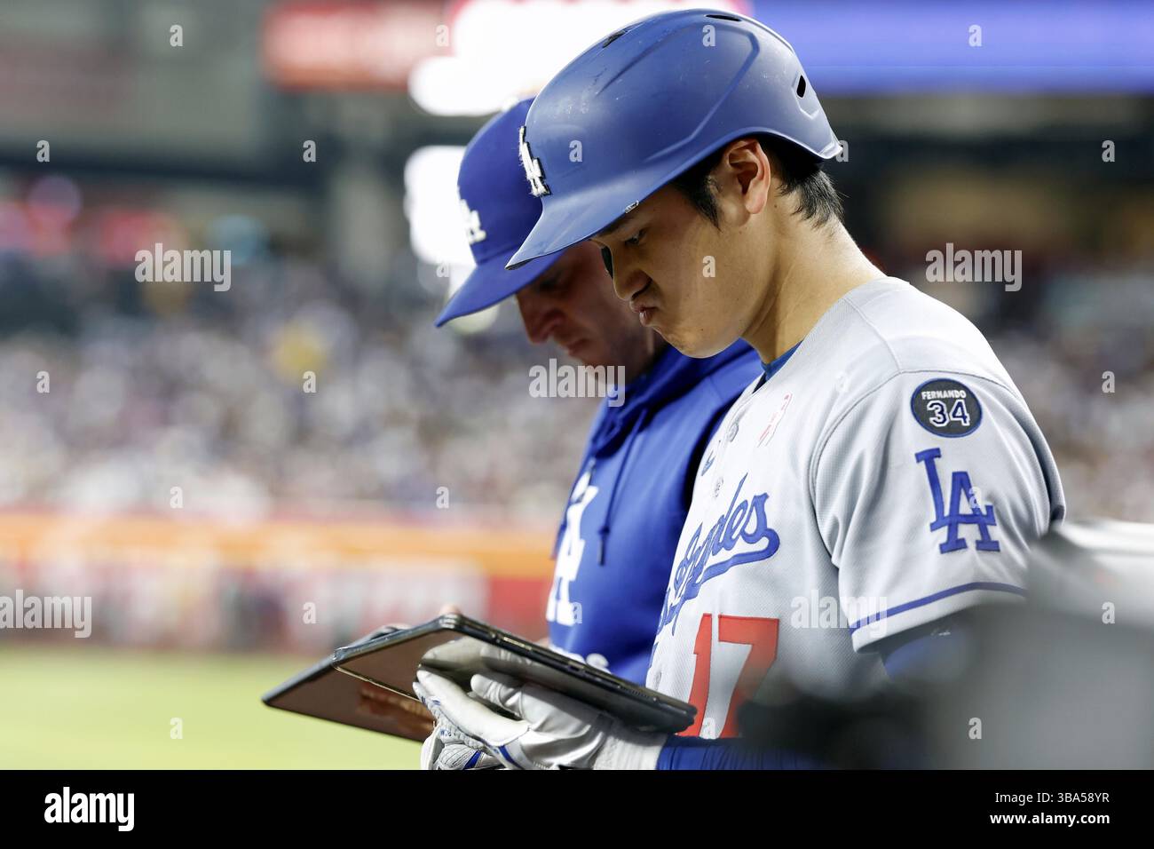 Shohei Ohtani of the Los Angeles Dodgers checks a tablet device during ...