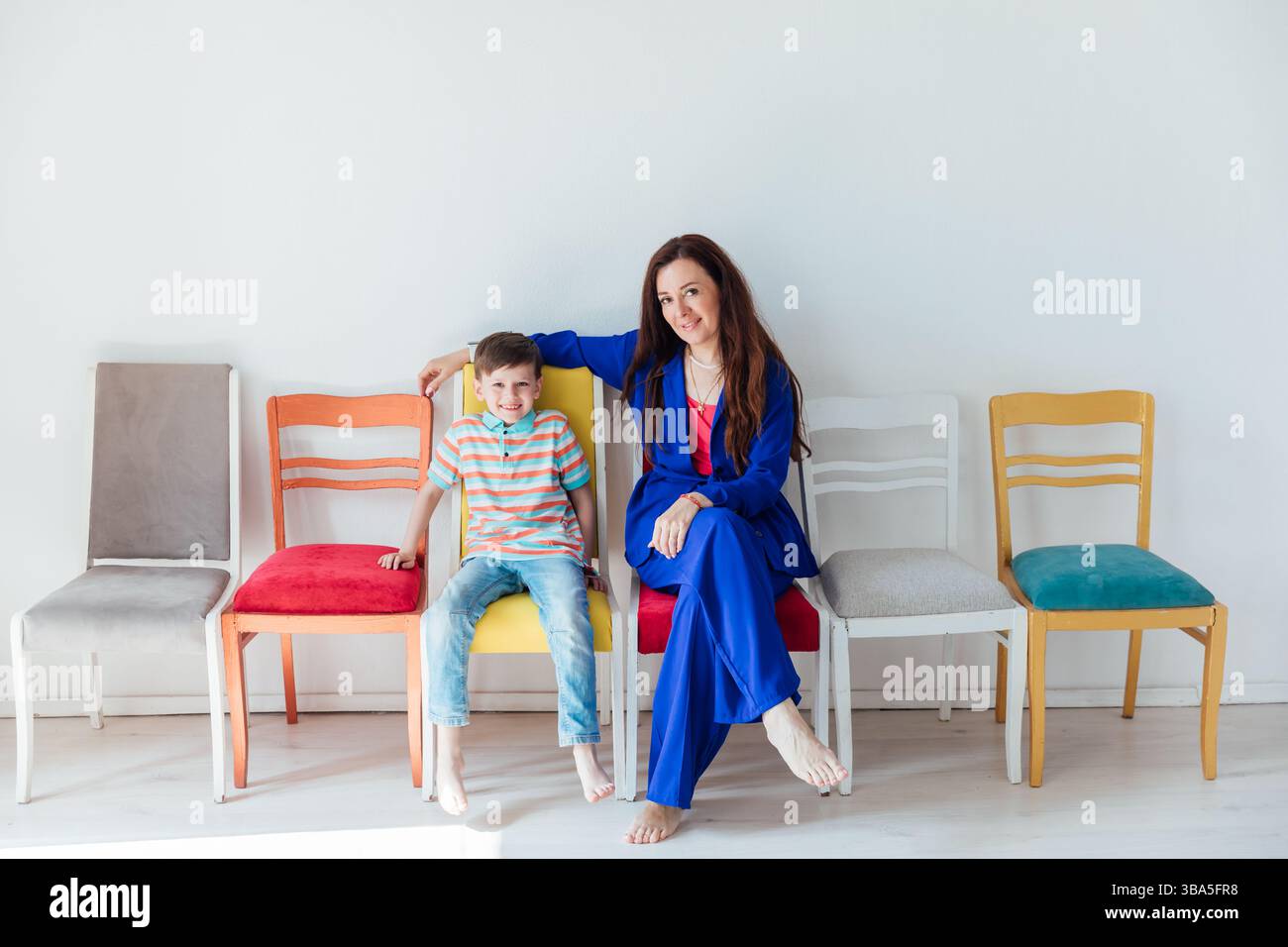 Woman and boy sitting on different chairs in room Stock Photo - Alamy