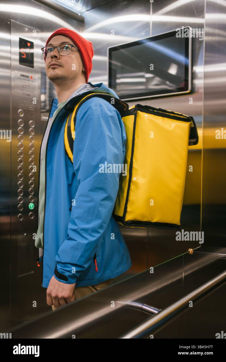 Delivery man wearing red woolen hat and blue jacket carrying yellow ...