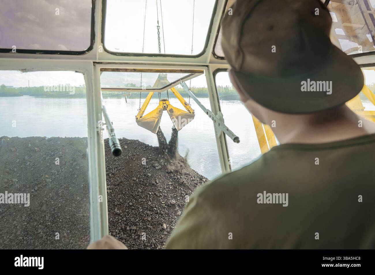 The operator, positioned inside the cabin of a floating crane, oversees ...
