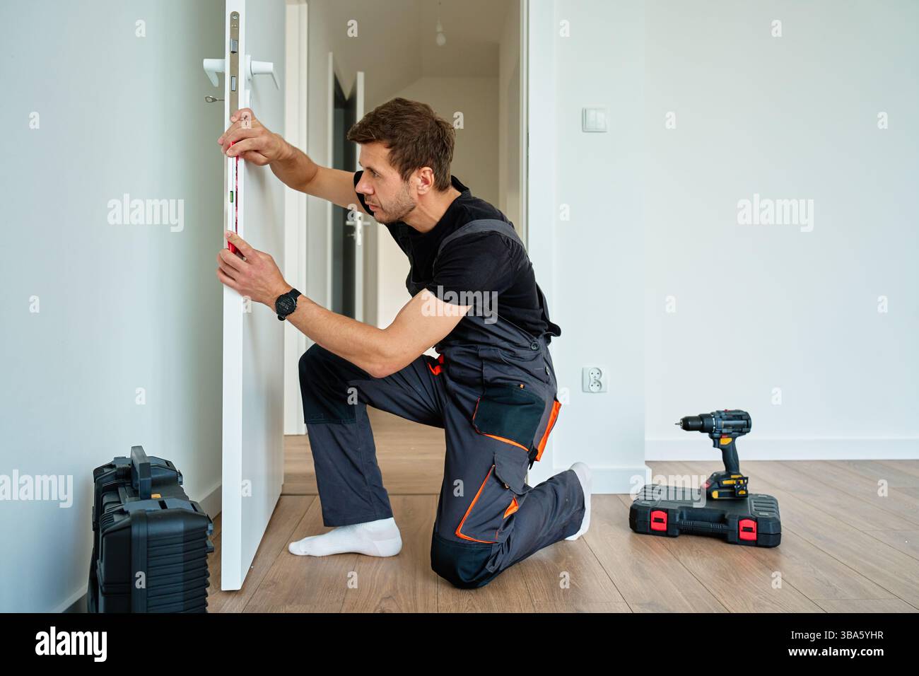 Man installing interior door using spirit level. Professional craftsman ...