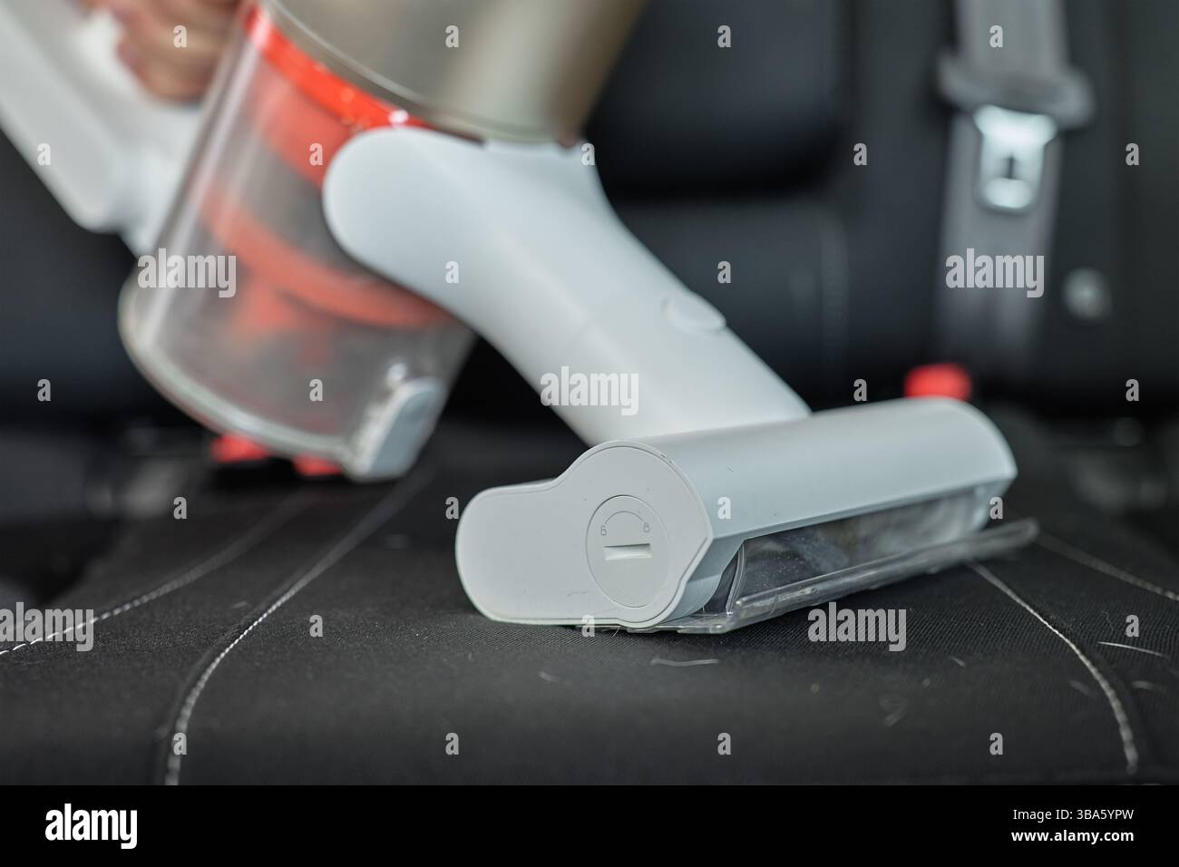 Handheld cordless vacuum cleaner vacuuming car seat upholstery. Modern ...