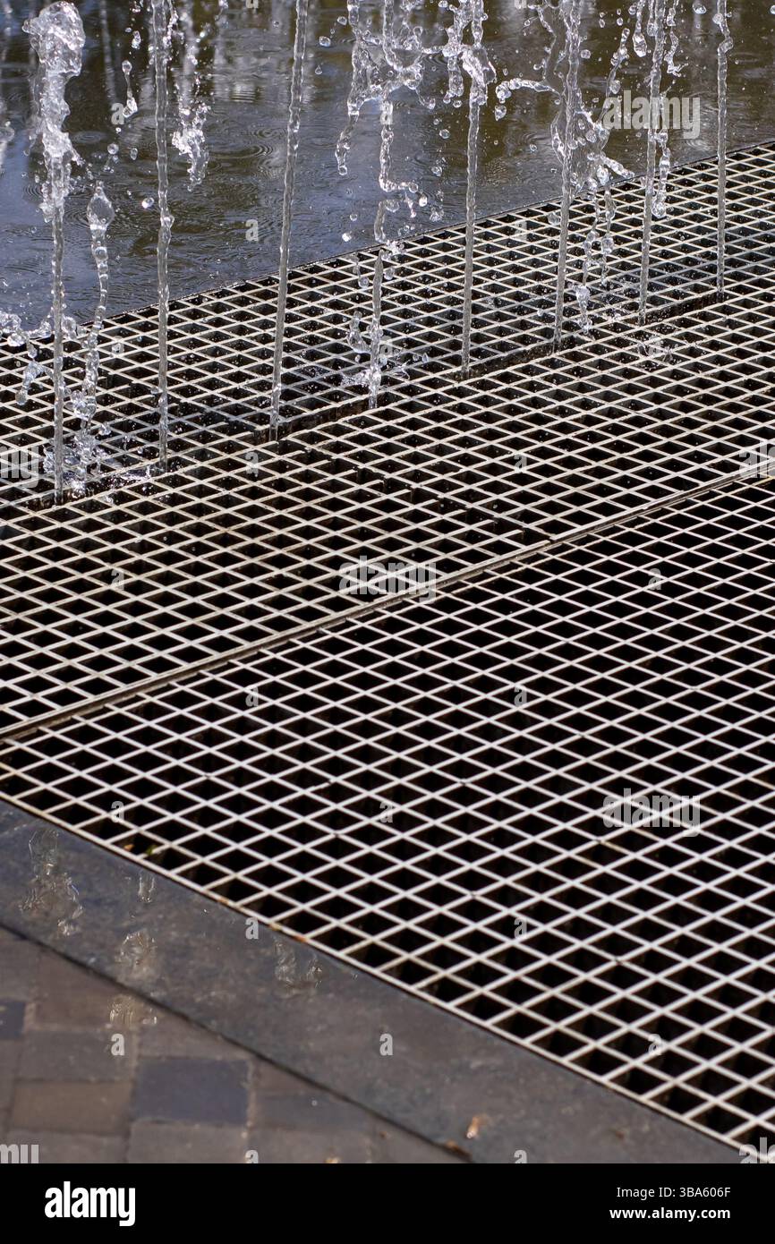 A detailed closeup of a metallic grate that is actively allowing water ...