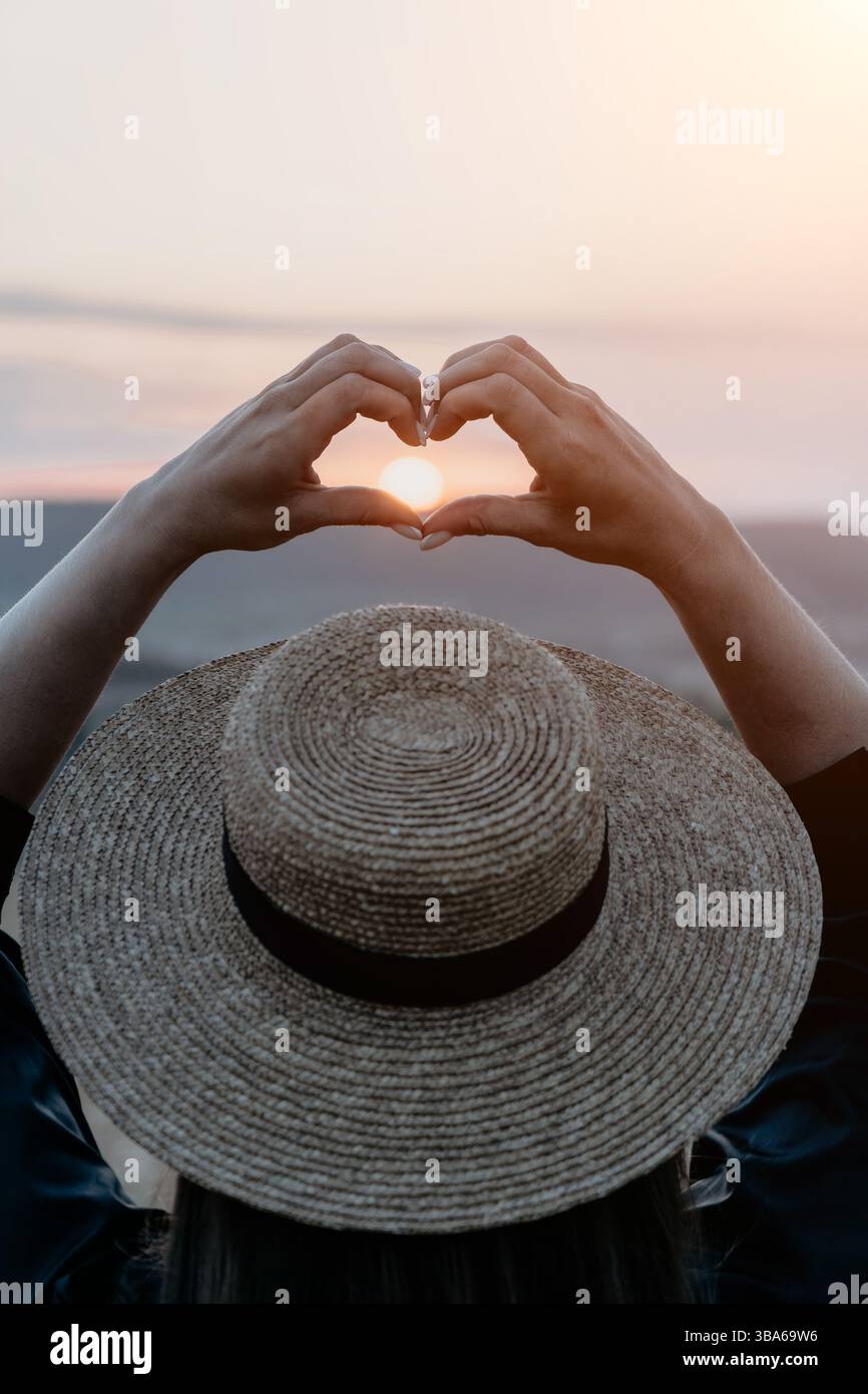 Sunset Heart Hands Hat: Woman creates heart-shaped sunset symbol ...