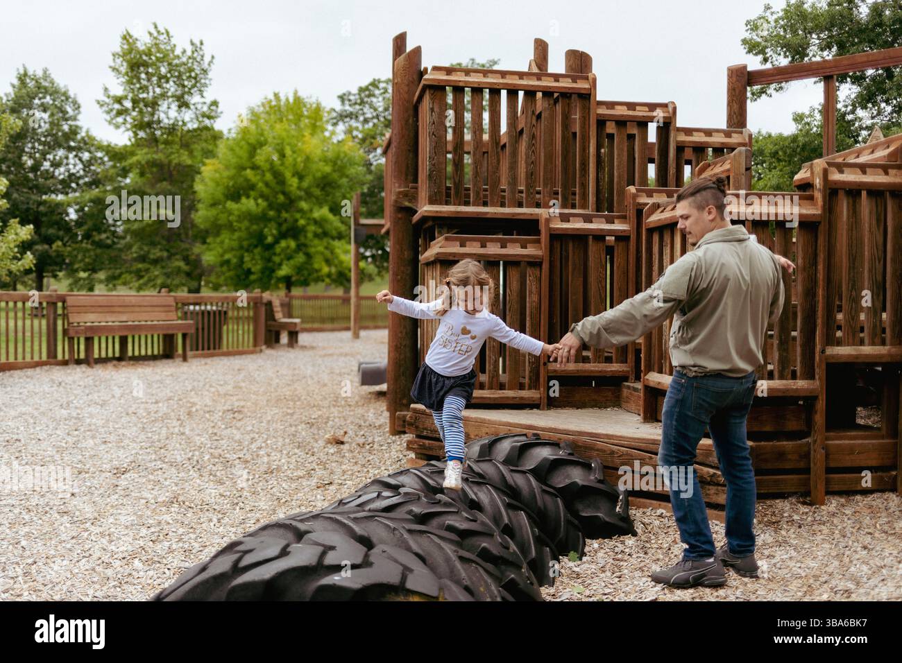 Joyful father playing with daughters at outdoor park playground Stock ...