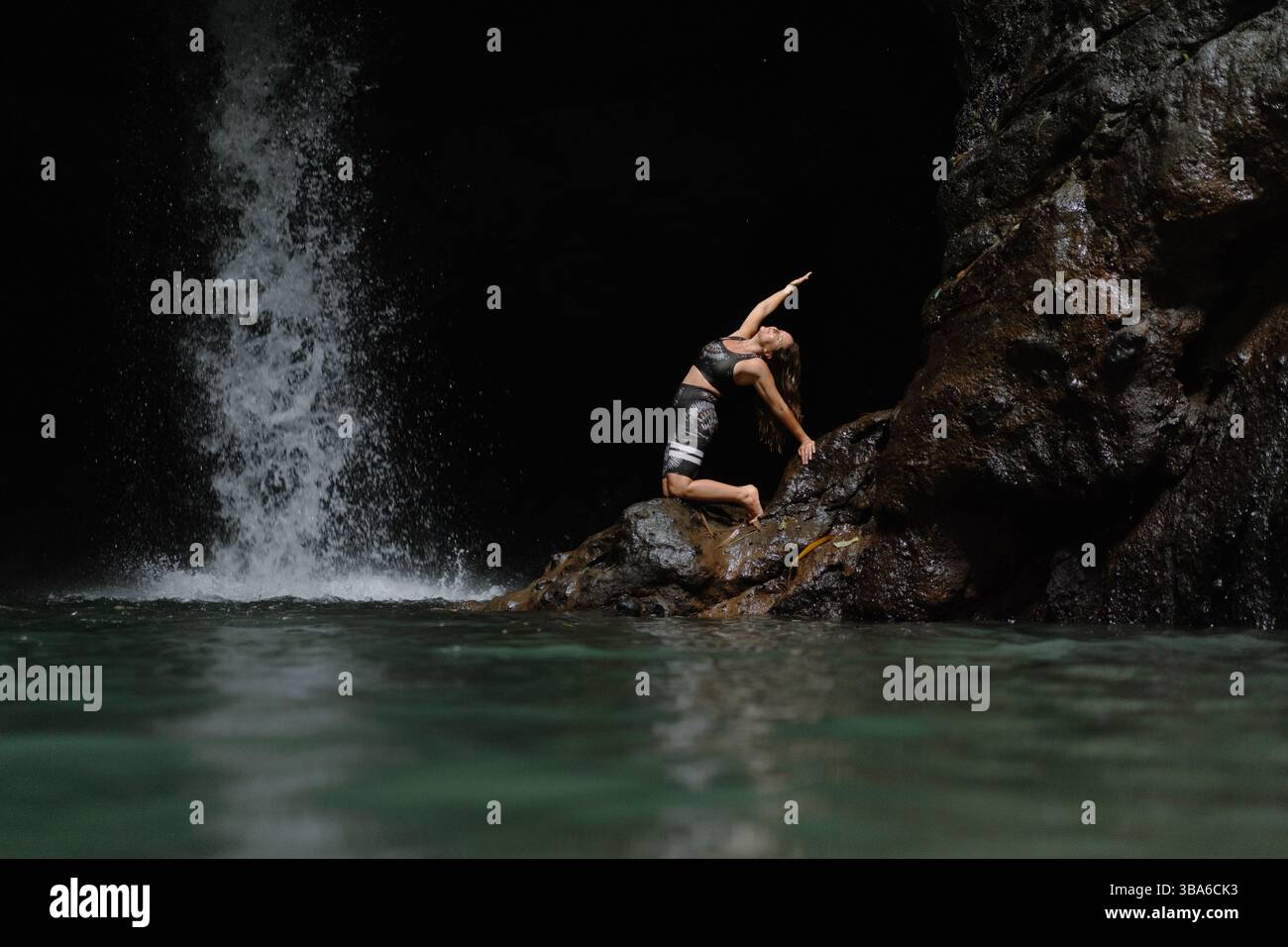 Woman practising yoga in front of waterfall on the island of Bali Stock ...
