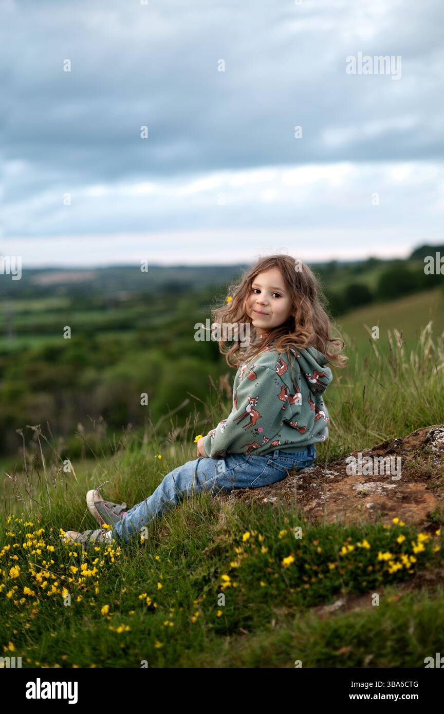 A girl sitting on slope turned around and looks at the camera Stock ...