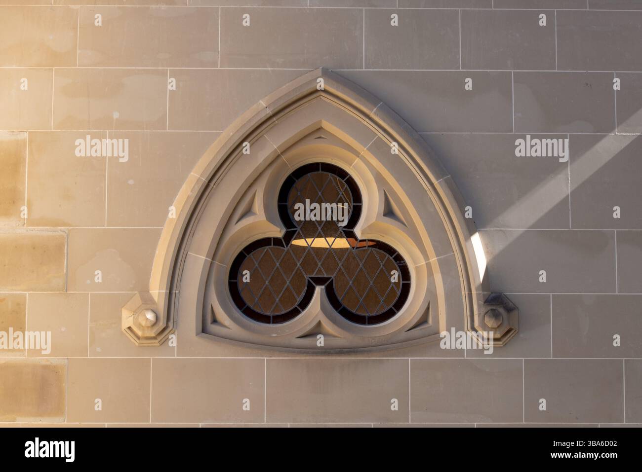 Close up sunlight illuminating trefoil window on sandstone facade Stock ...