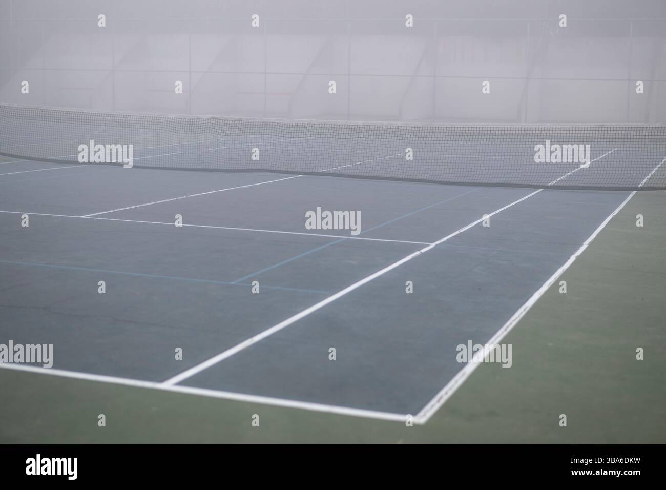 blue tennis court enveloped in grey blurring fog Stock Photo - Alamy