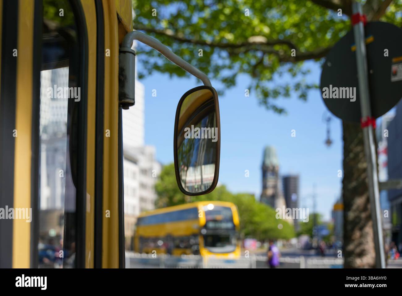 Bus mirror with Berlin backdrop. Side view of a yellow bus with a focus ...