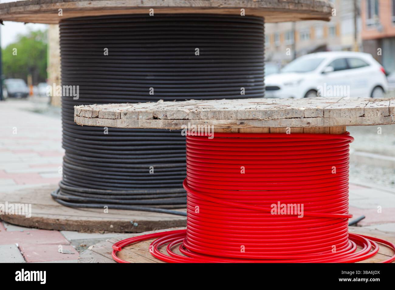 Two wooden spools with new electrical cables wrapped in black and red ...
