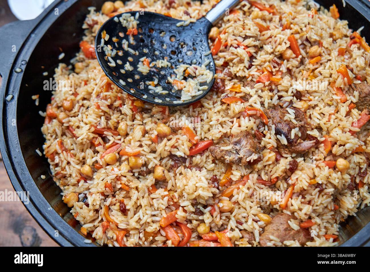 Top view of ready-made oriental pilaf in a black cauldron placed on an ...