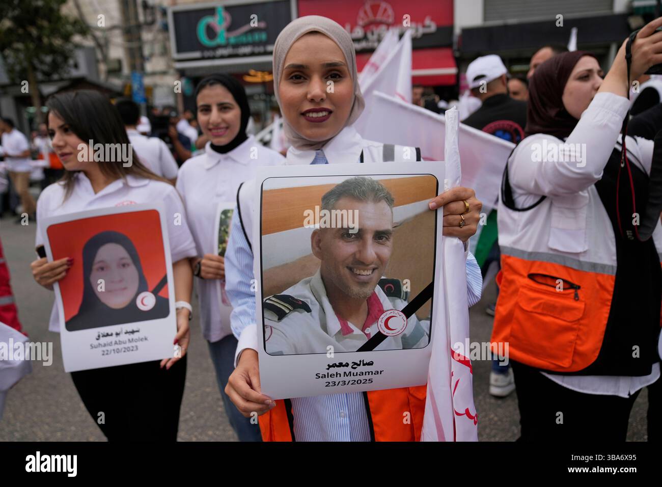 Paramedics hold posters with names and pictures of fellow relief ...