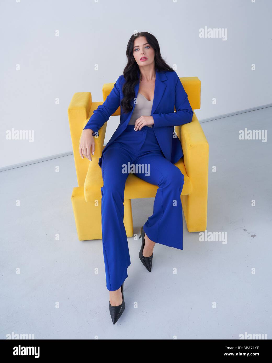 Confident woman in blue suit sitting on chair Stock Photo - Alamy