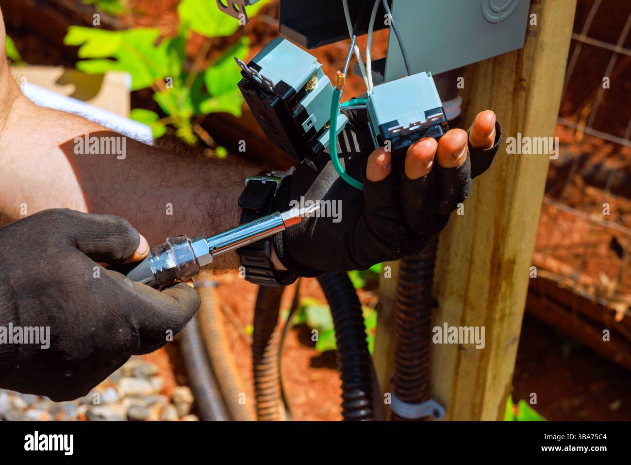 Tech fixes garden electrical outlets connections with tools, ensuring ...