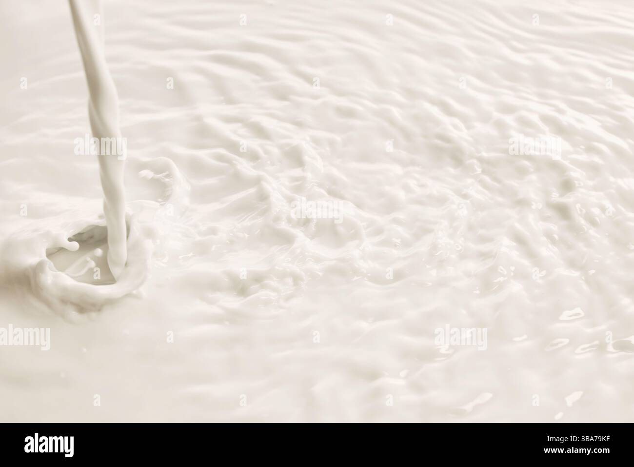 Milk pours onto milky surface forming waves and smooth textures under ...