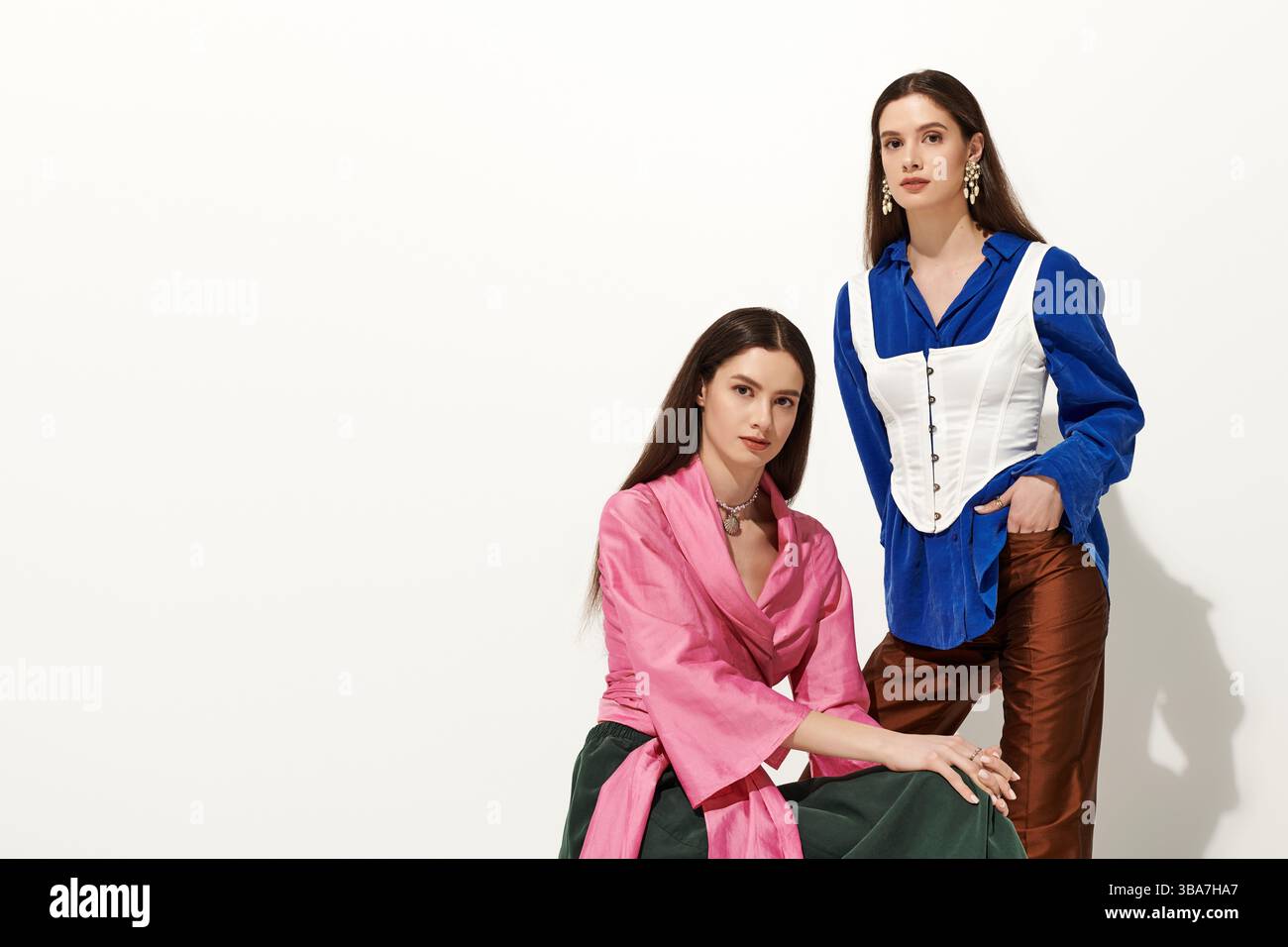 Two beautiful young twin sisters pose elegantly while celebrating their ...