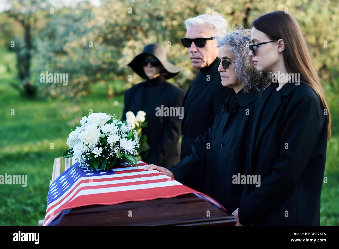 Row of family members in sunglasses and mourning clothes standing by ...