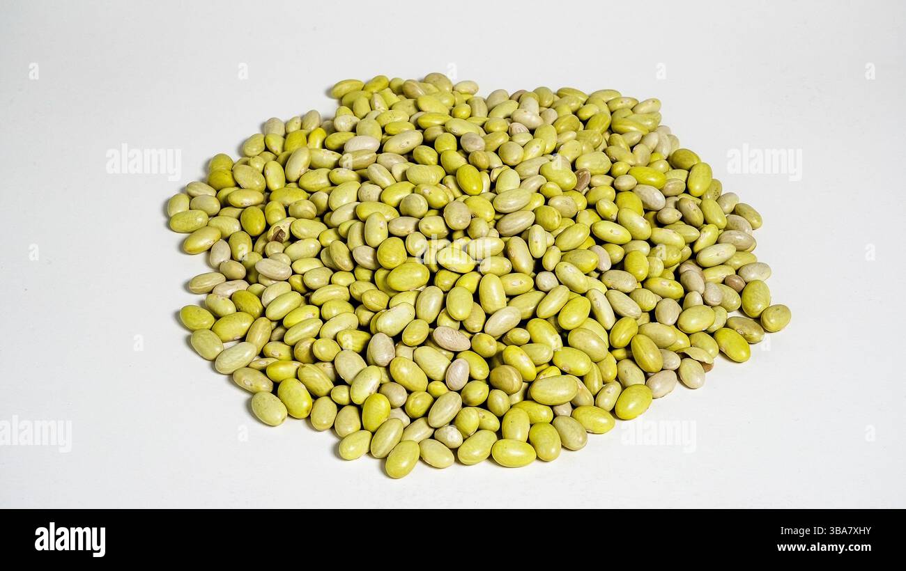 Yellow Canary beans lie scattered across a white surface, displaying ...