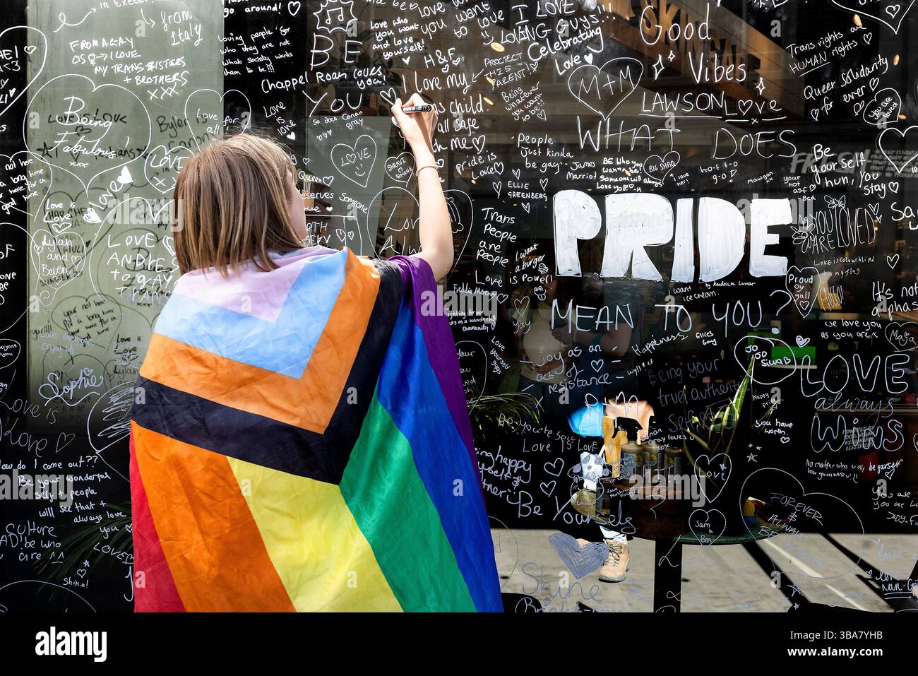 A young woman signs a window display in aid of Pride at Exeter Pride ...